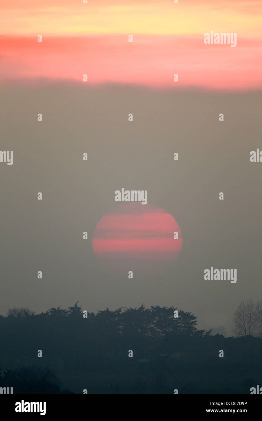 Pink sun descending behind cloud Stock Photo - Alamy