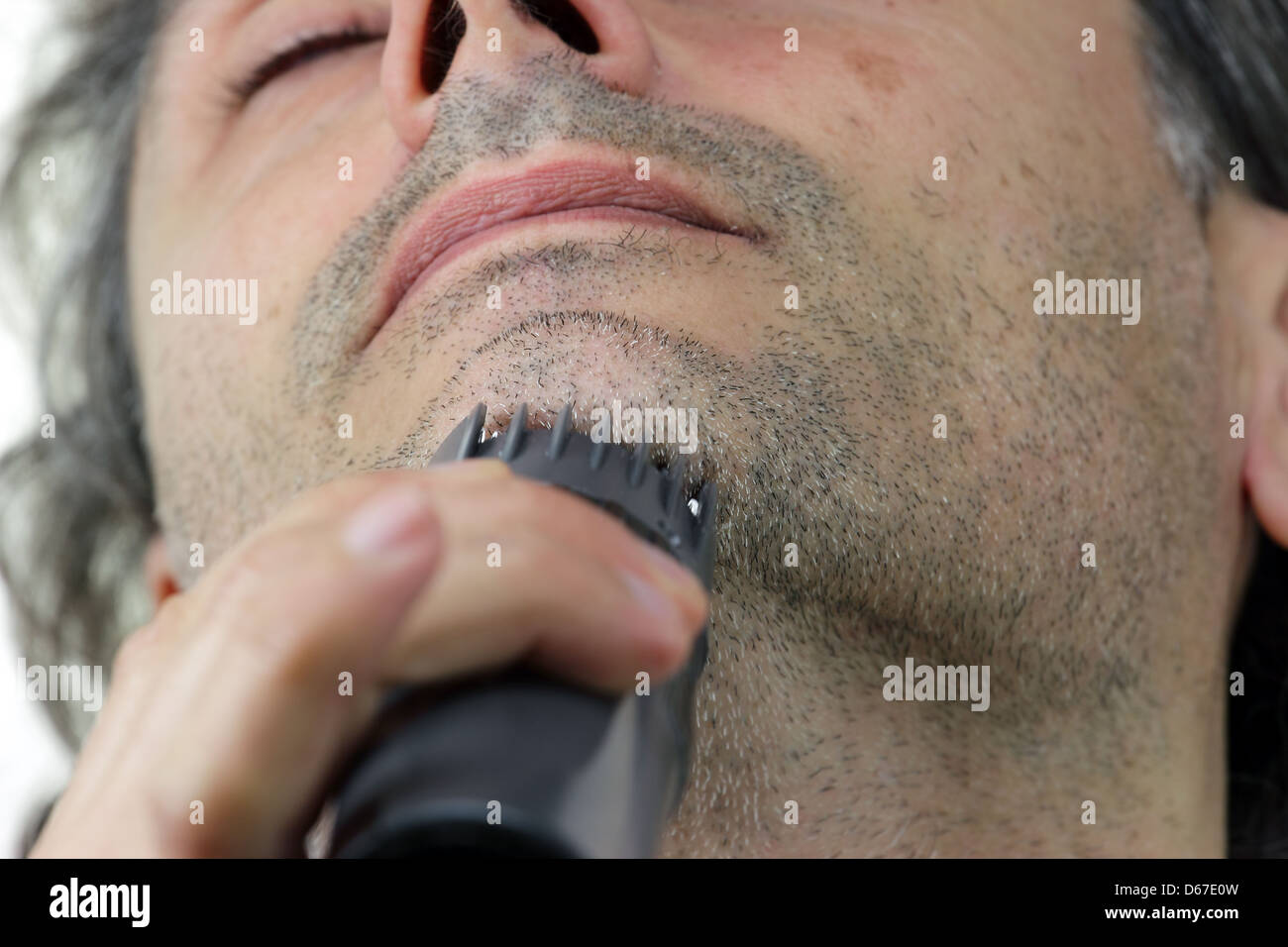 Man shaving his chin using electric shaver Stock Photo - Alamy
