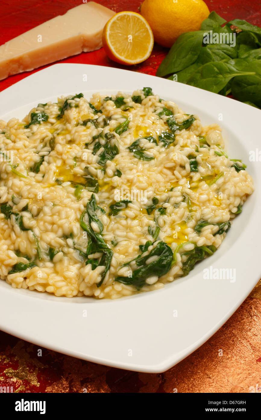 Basil and lemon risotto in a white dish with cheese wedge whole and ...