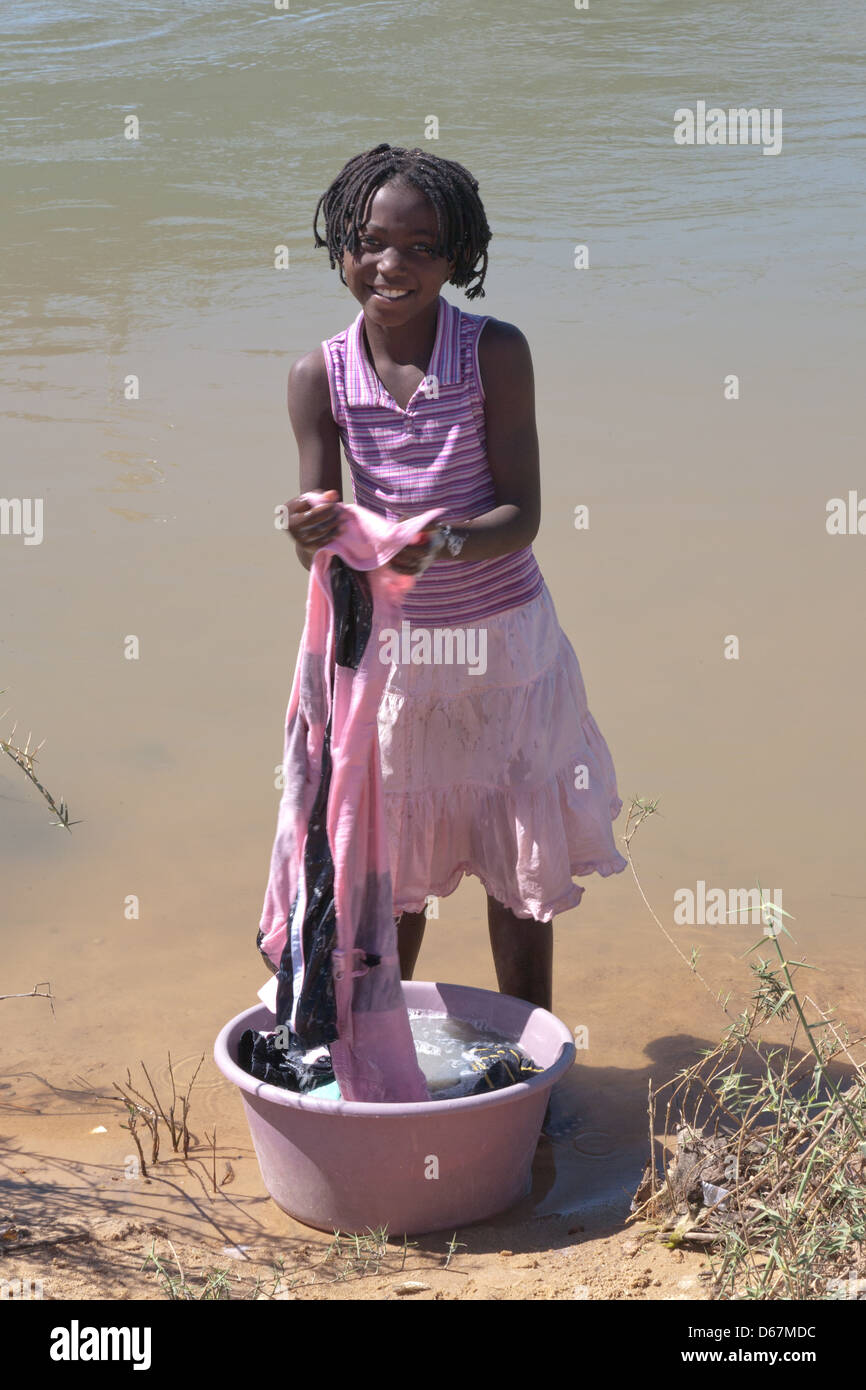 African girl washes clothes in bucket with water collected from Stock ...