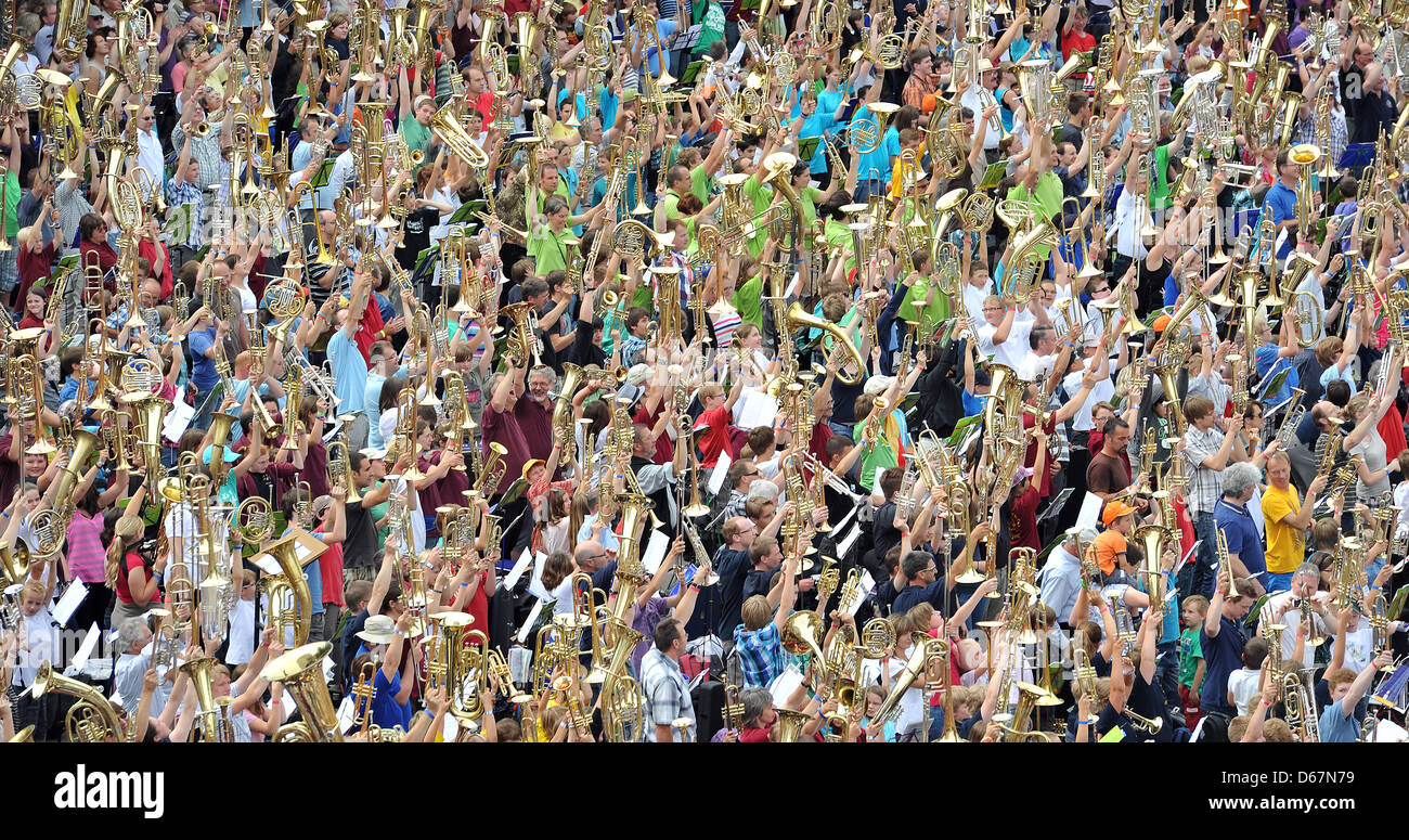 Brass players lift their instruments to greet the conductor before the ...