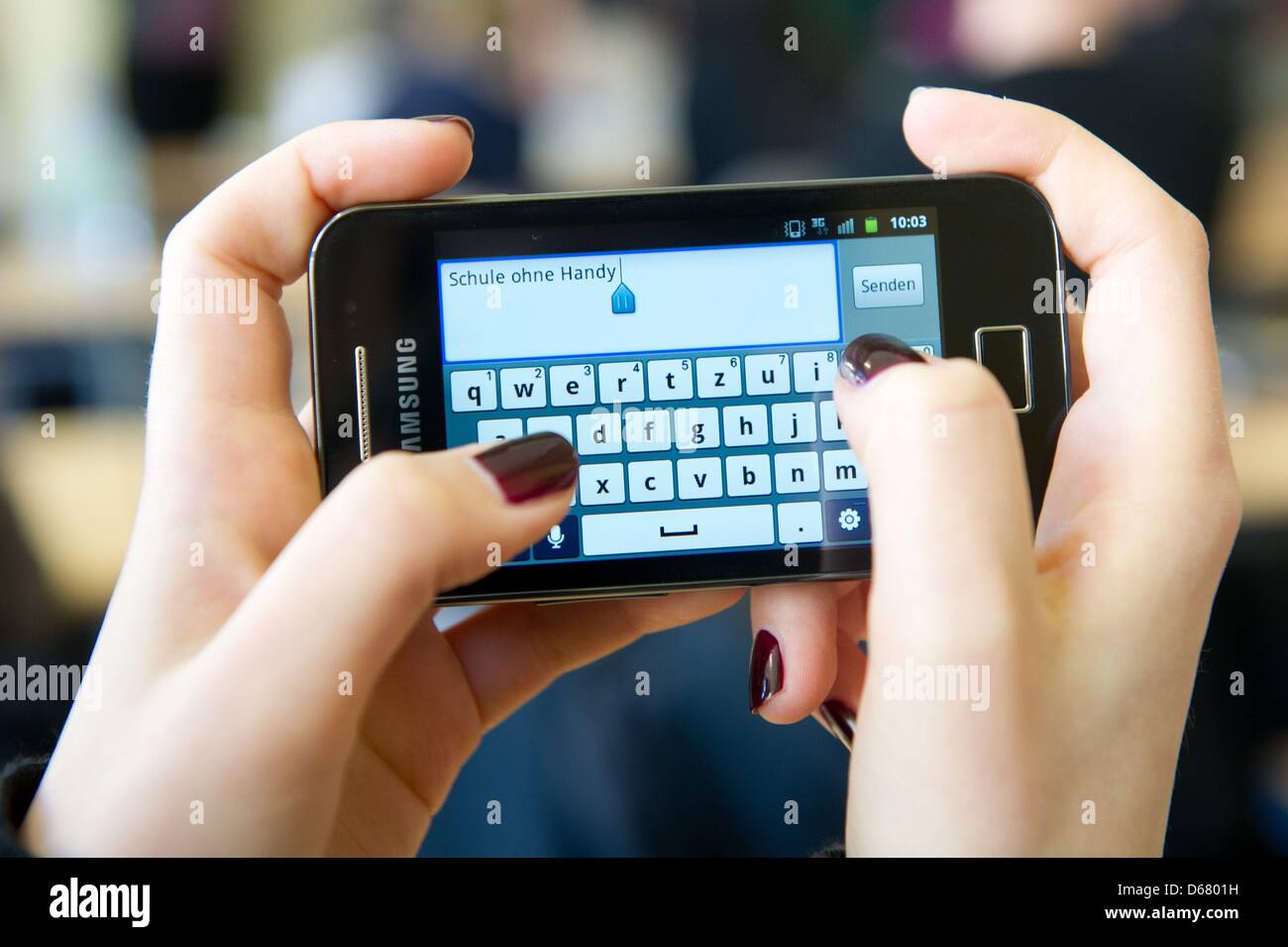 A pupil of the tenth grade types a message on her smart phones at the ...