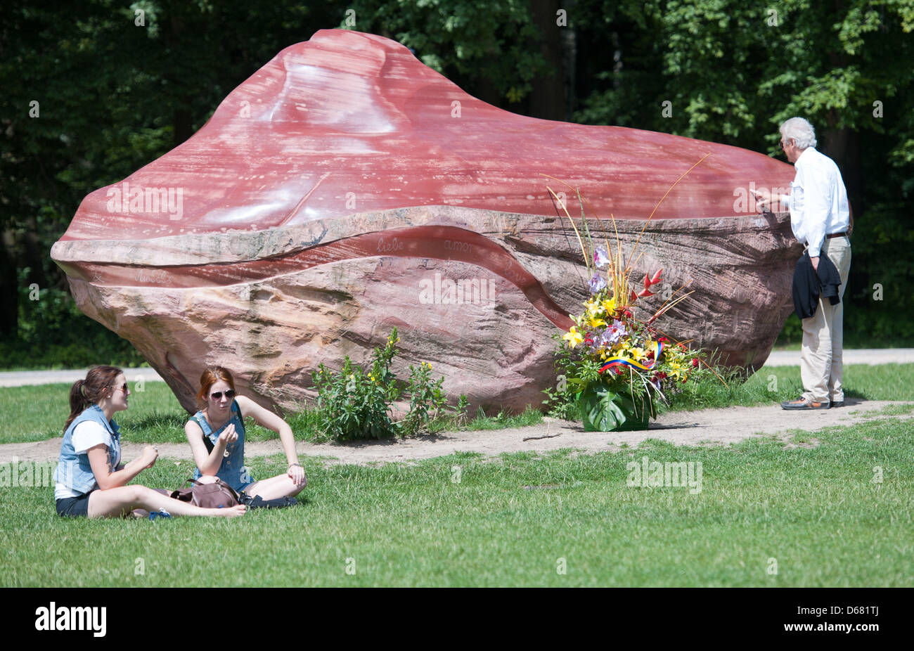 Tourists sit next to the Kueka stone at Tiergarten public park in ...