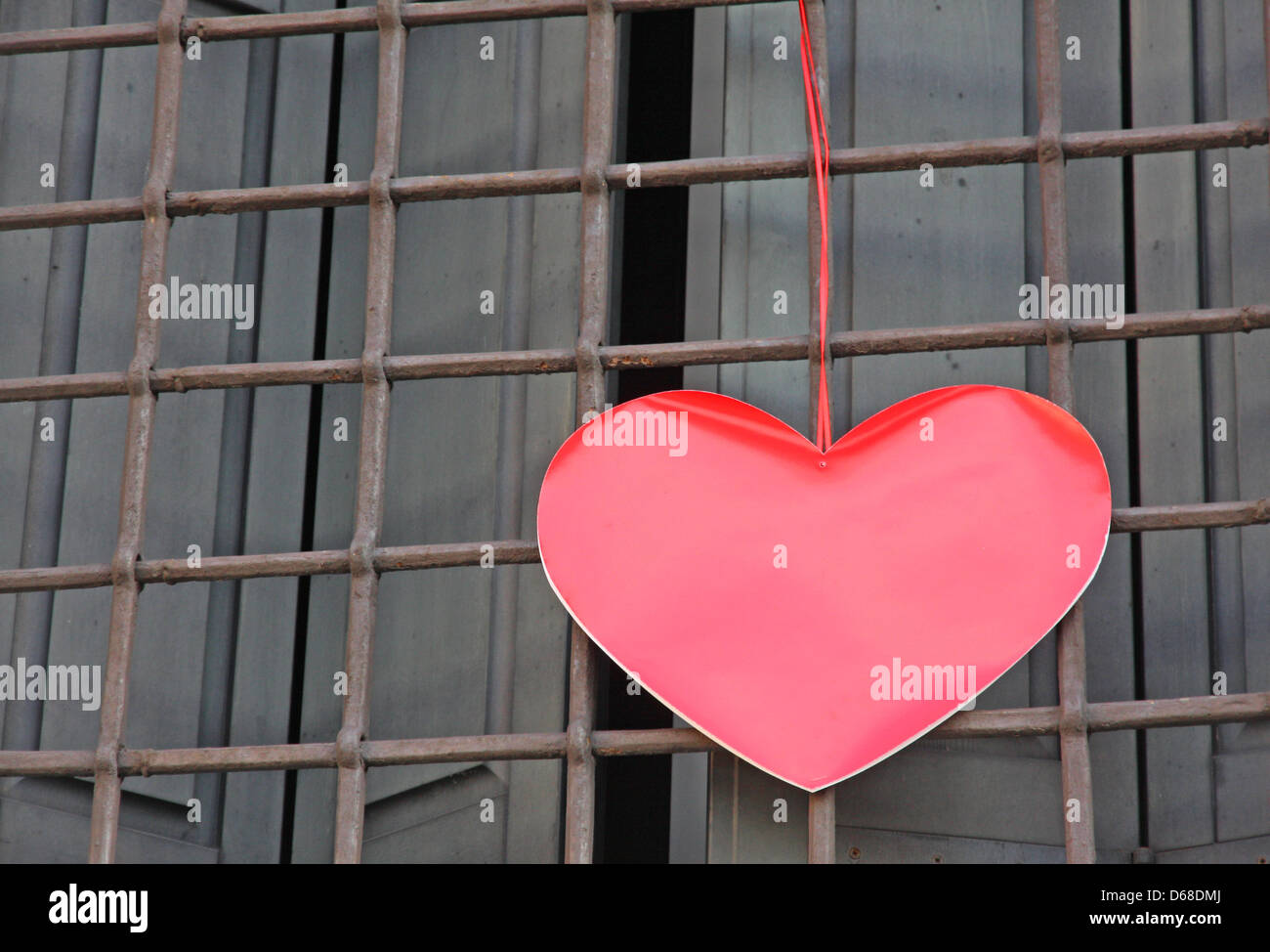 red heart hanging on the grid of a window outside a building on ...