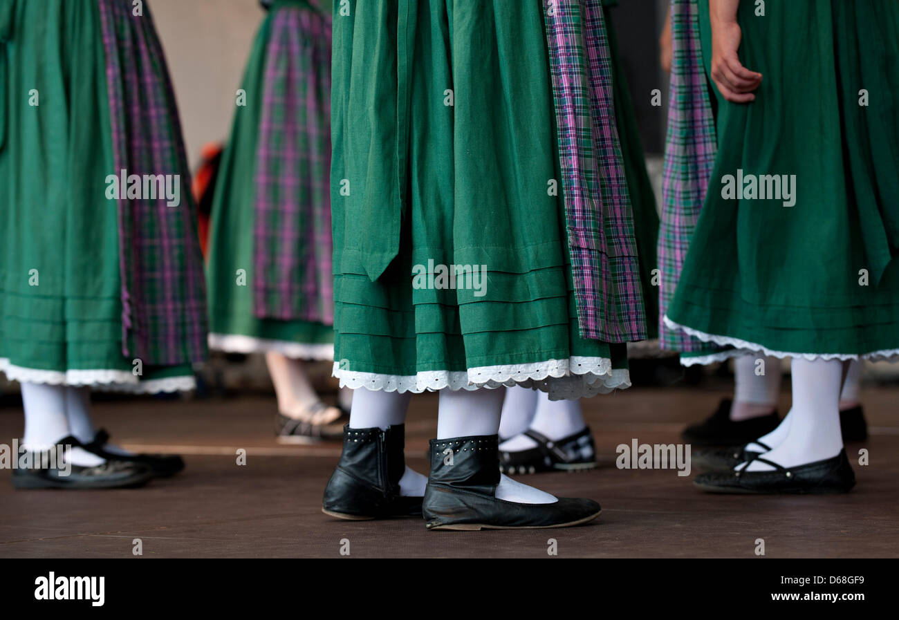 A group of young girls dressed in traditional German costumes dance on ...
