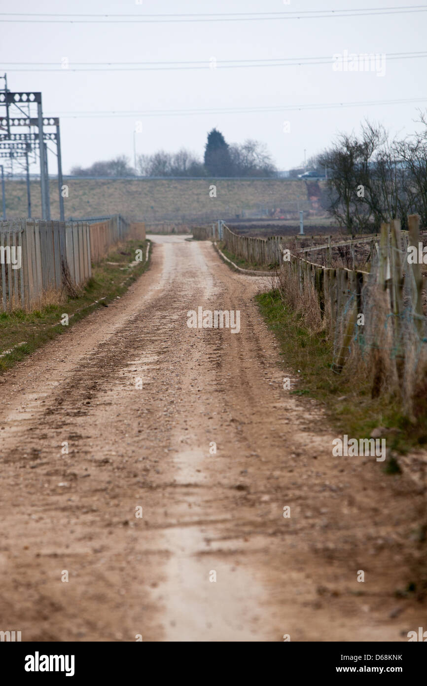 A narrow road covered in dried mud runs alongside a railway line Stock ...