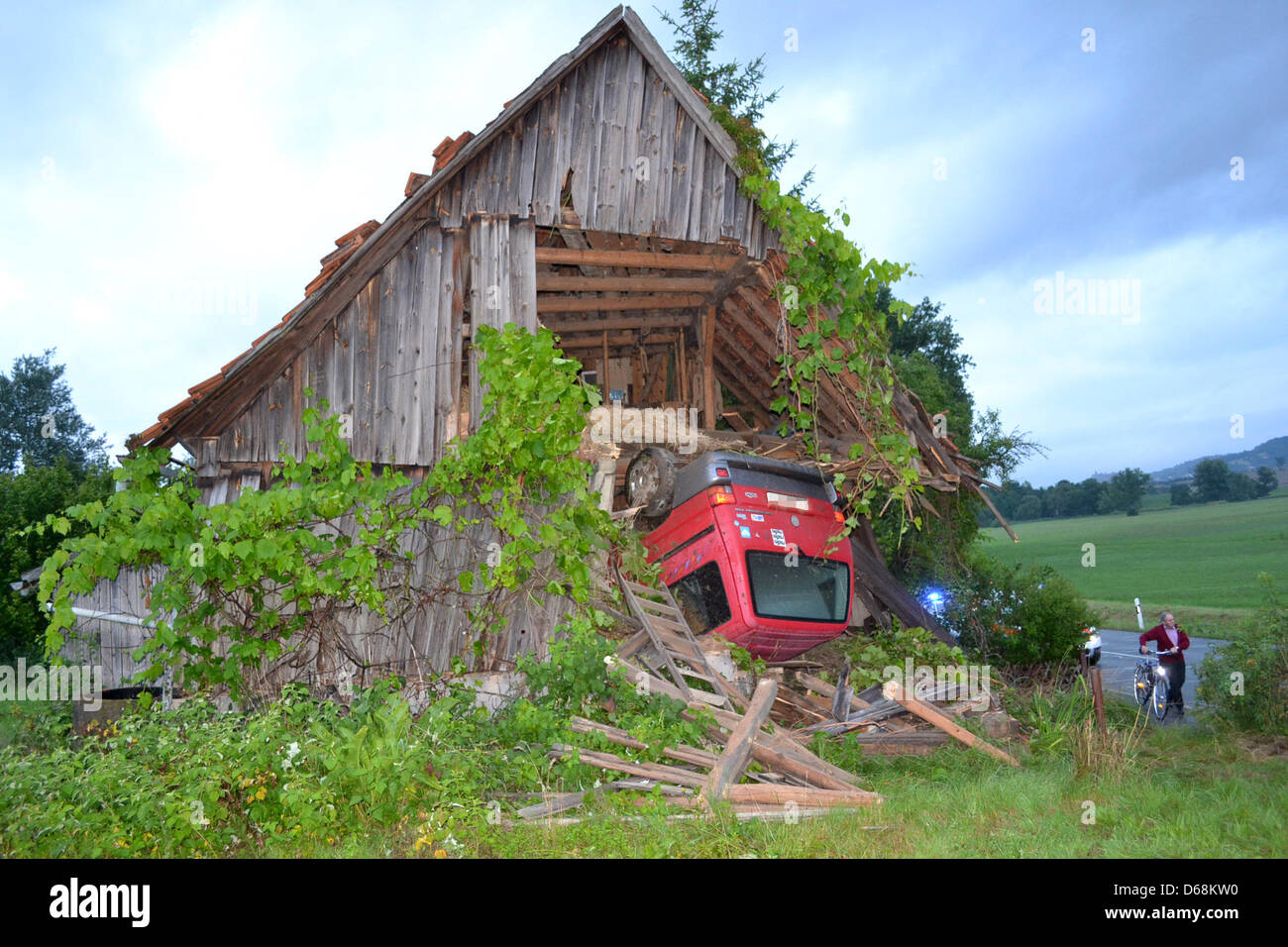 Fire fighters stand in front of a barn into which a red mimi van has ...
