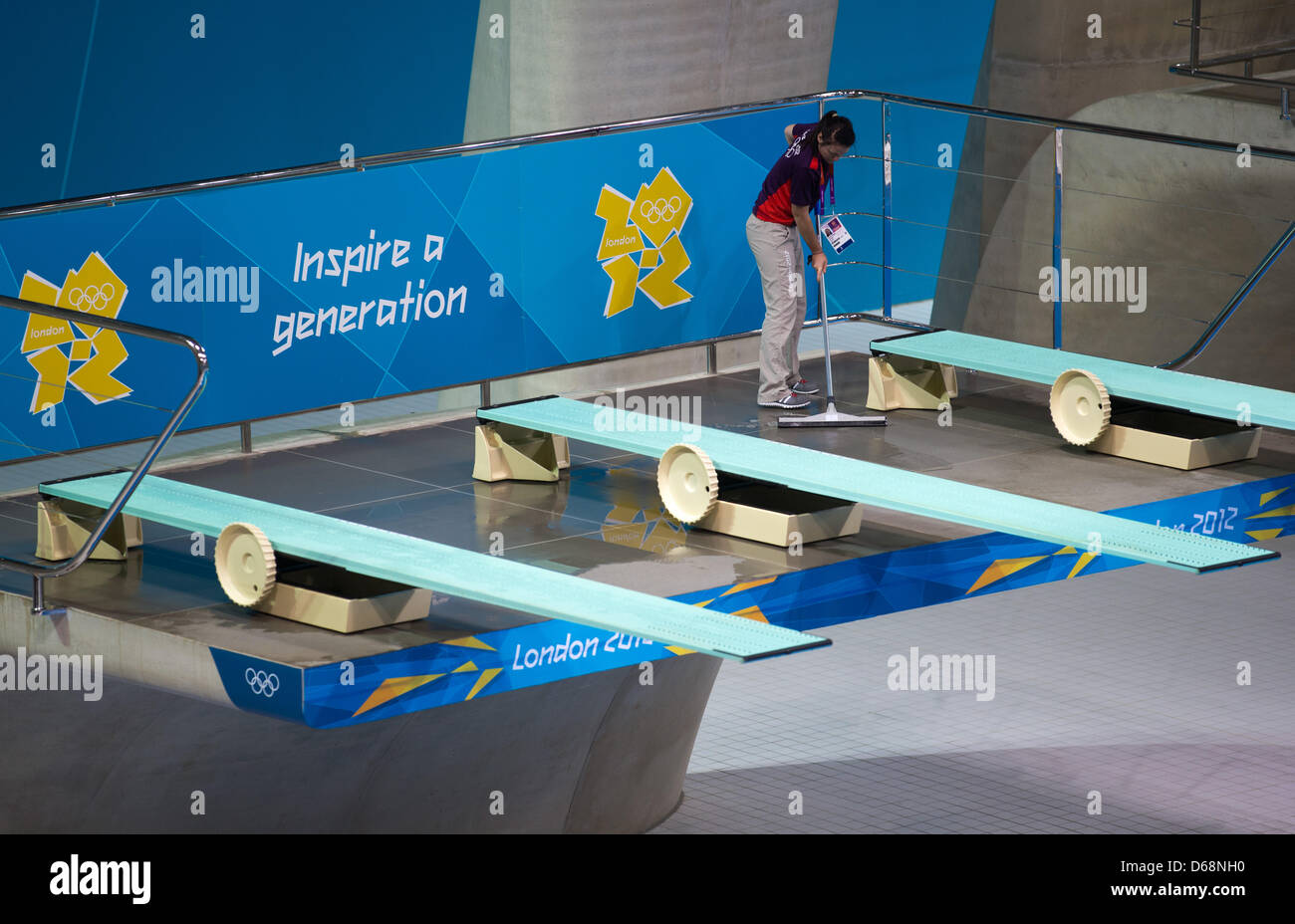 A Volunteer cleans the diving board platform at the Aquatics Center in ...