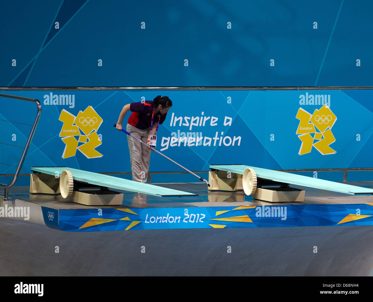 A Volunteer cleans the diving board platform at the Aquatics Center in ...
