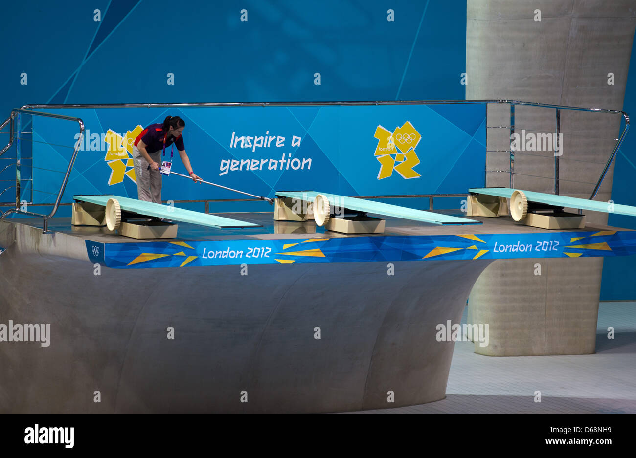 A Volunteer cleans the diving board platform at the Aquatics Center in ...