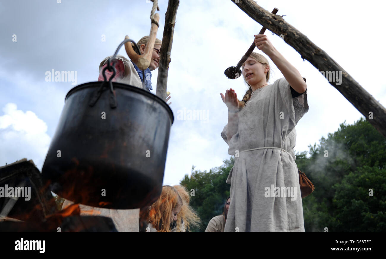 A student tastes some stew she has prepared at the stone age park near ...