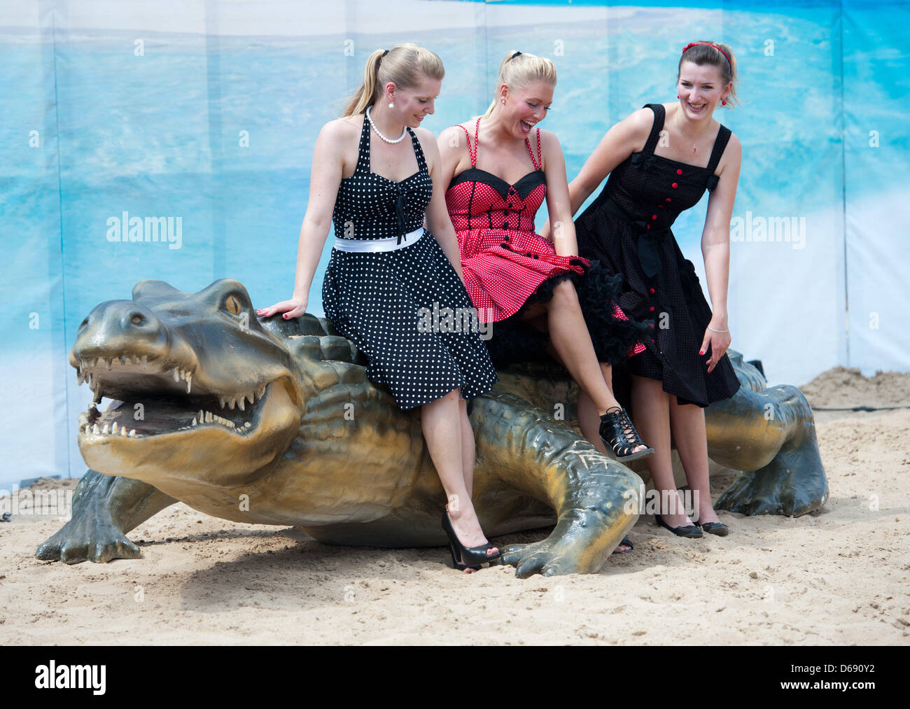 Models pose for the camera on a six metre long plastic alligator at a ...