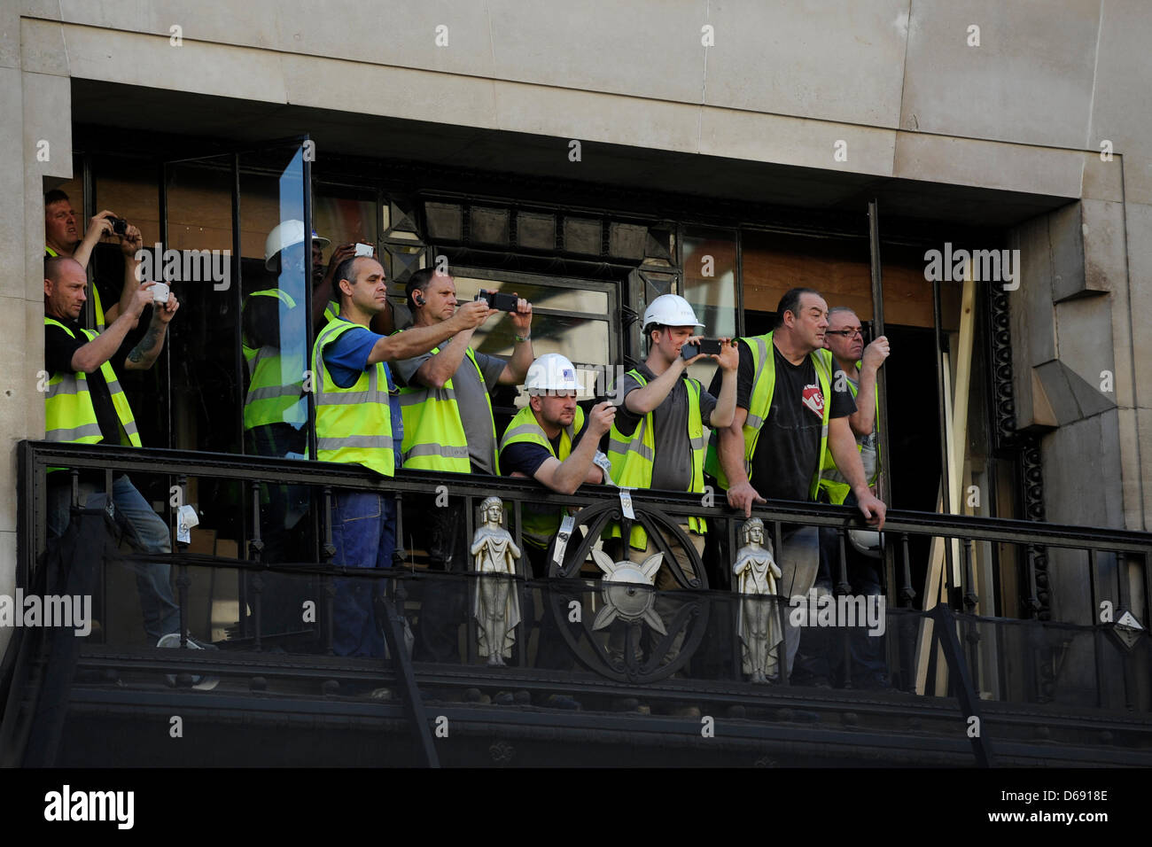 Workers take pictures as a torch bearer carrries the Olympic Torch ...