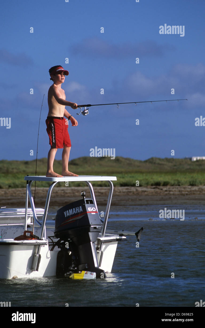 Young boy fishing for speckled trout and redfish from a boat near Port ...