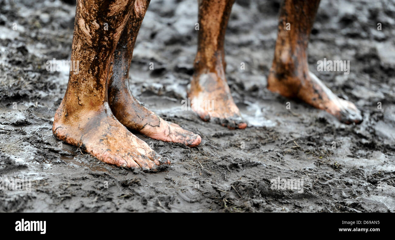 Two festival visitors stand barefoot in the mud on the camping site of ...