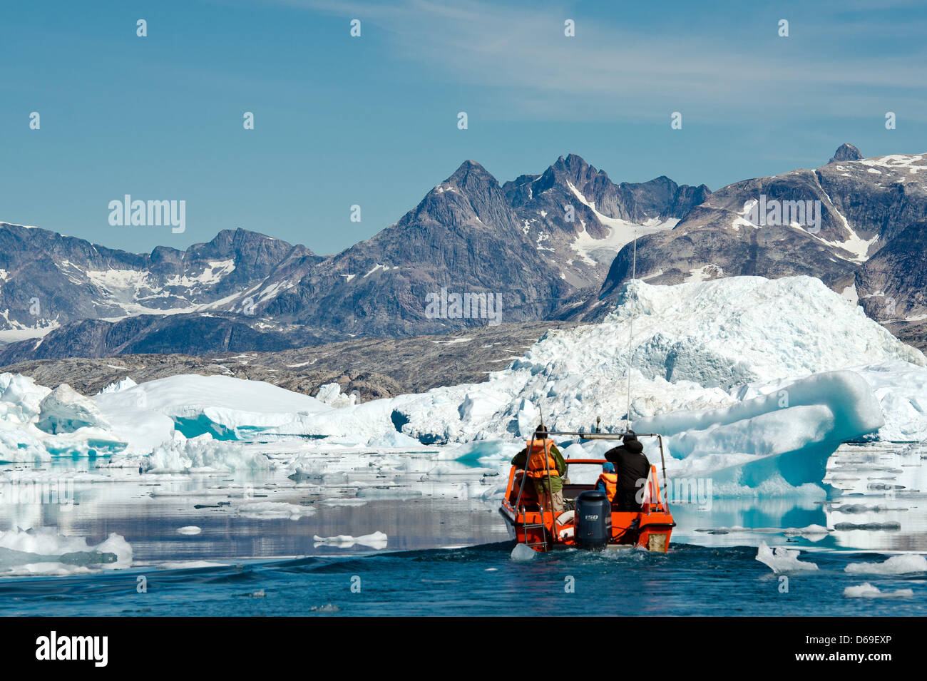 An Inuit steers a boat with tourists between icebergs in the Sermilik ...