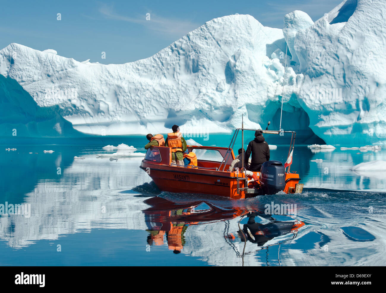 An Inuit steers a boat with tourists between icebergs in the Sermilik ...