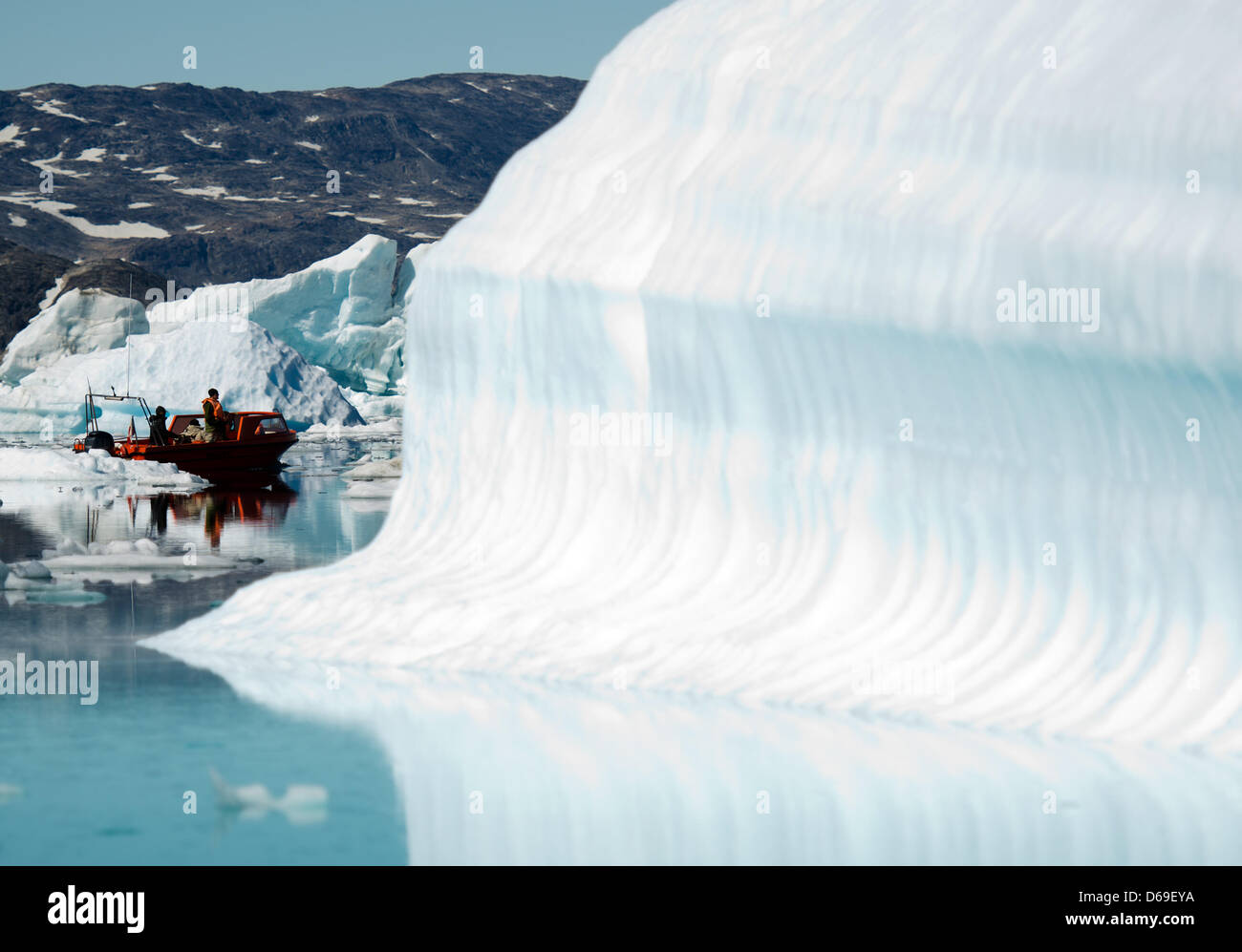An Inuit steers a boat with tourists between icebergs in the Sermilik ...