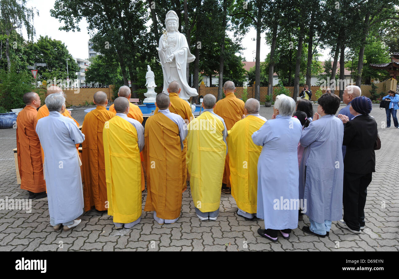 Buddhist monks and female pray in front of an Avalokitesvara statue ...