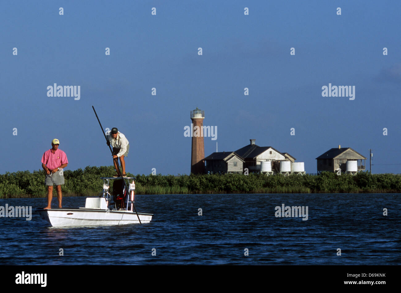Two men poling their boat and fishing for speckled trout and redfish ...