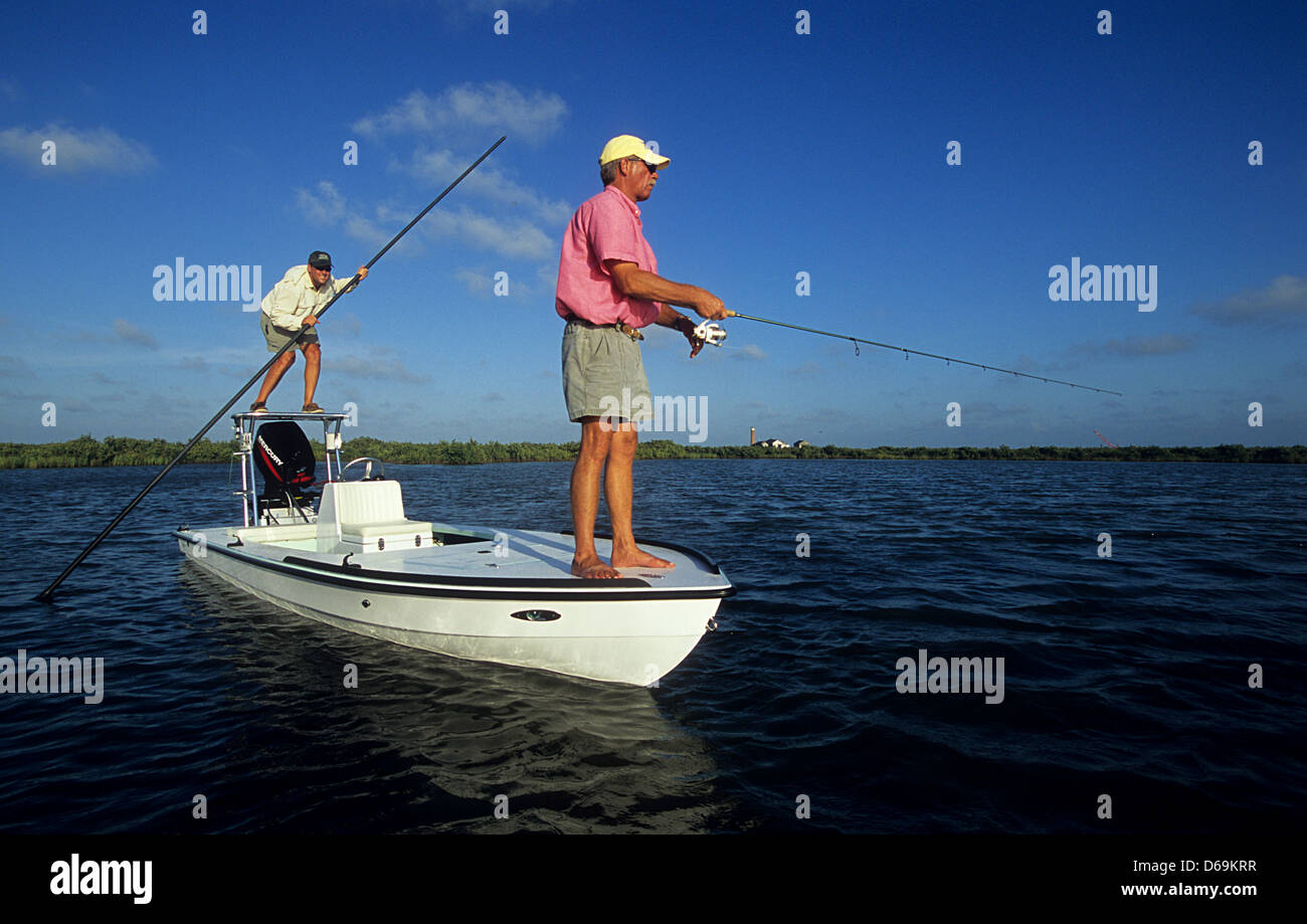 Two men poling their boat and fishing for speckled trout and redfish ...