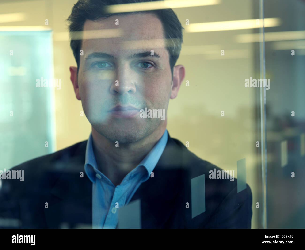 Businessman standing behind glass Stock Photo - Alamy