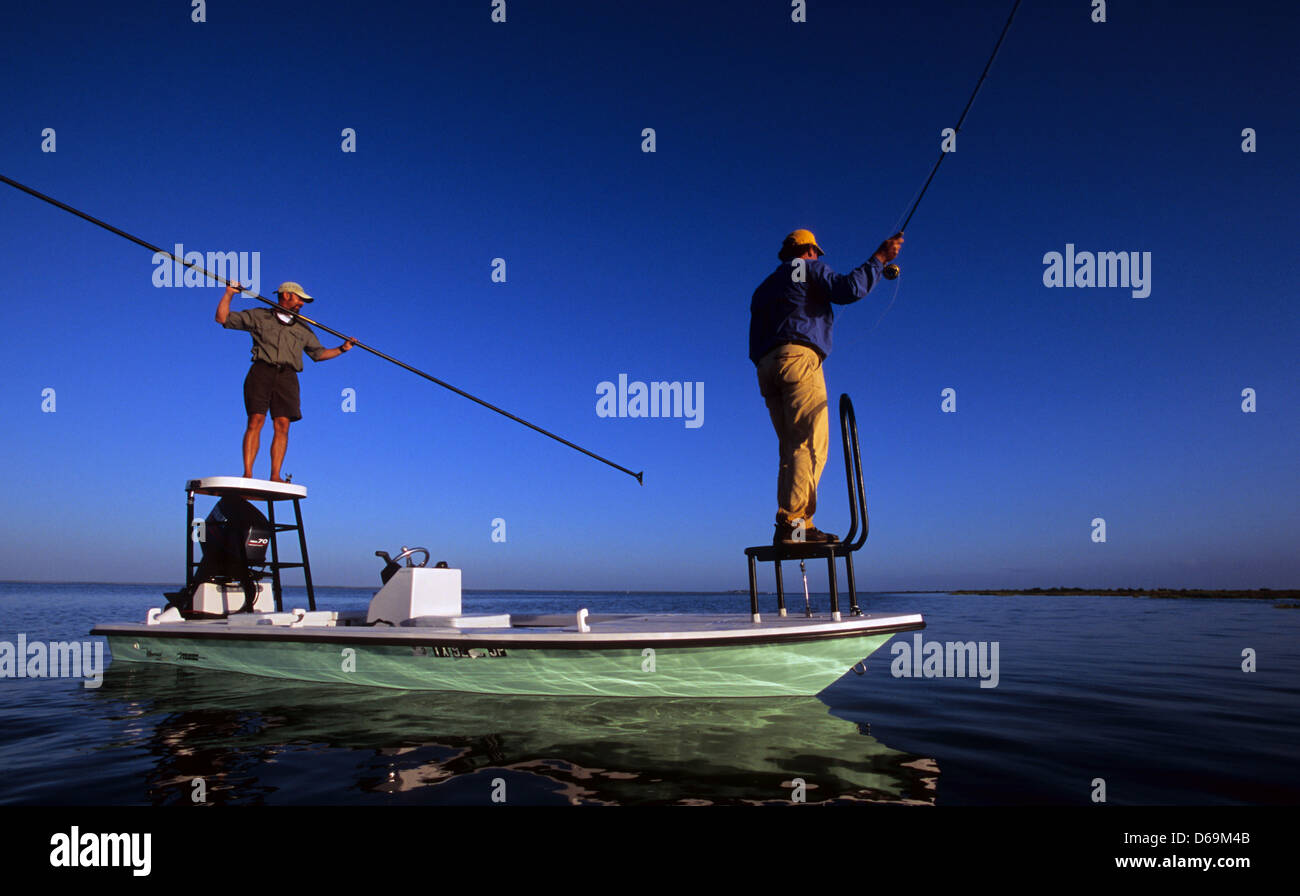 Fly fisherman and fishing guide poling their skiff and looking for ...