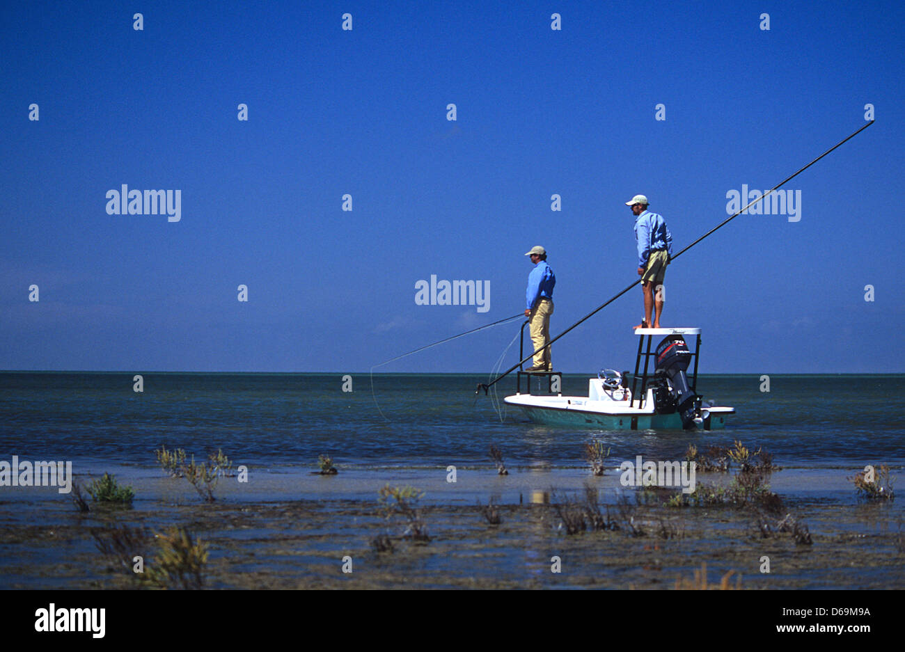 Fly fisherman and fishing guide poling their skiff and looking for ...