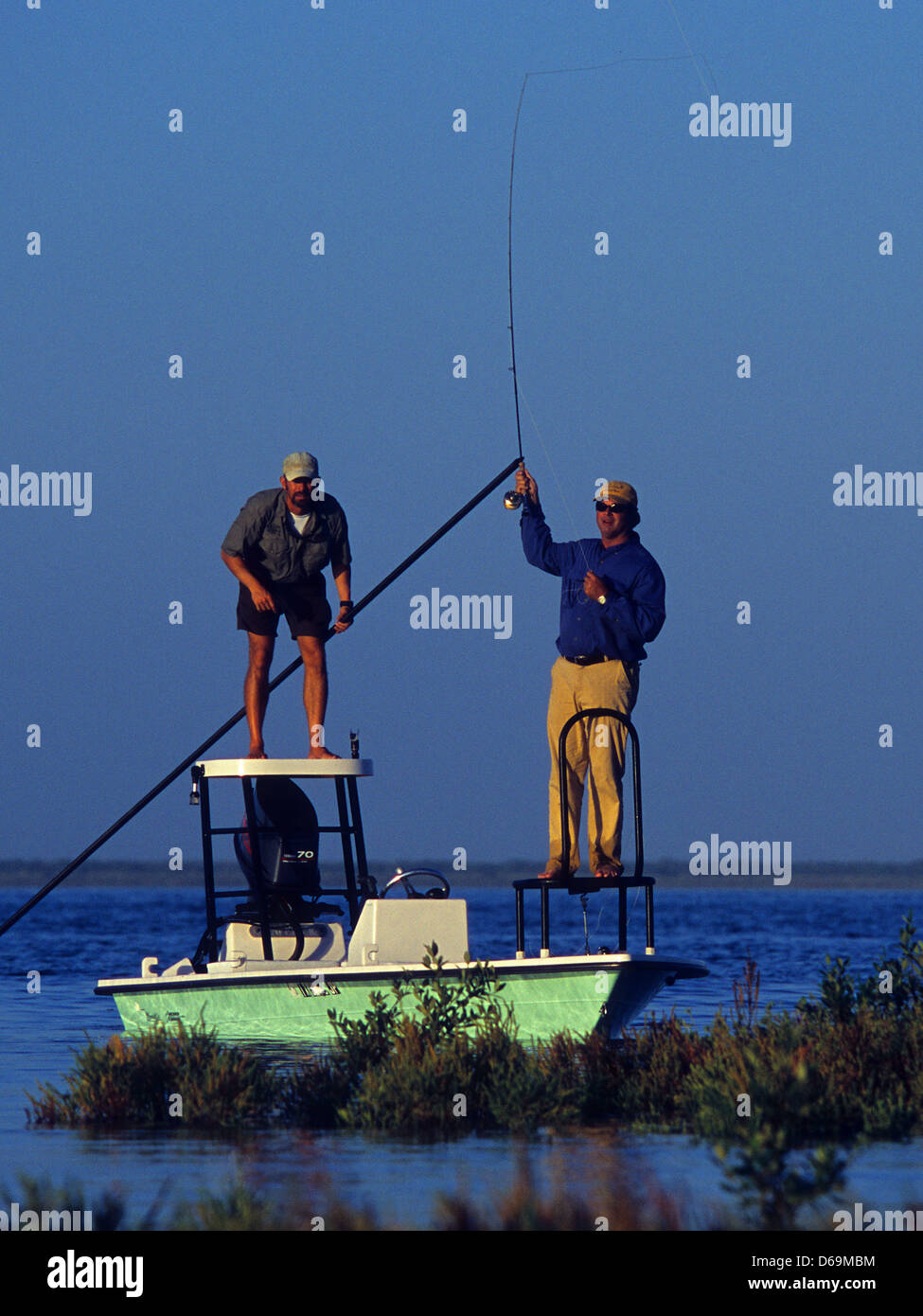 Fly fisherman and fishing guide poling their skiff and looking for ...