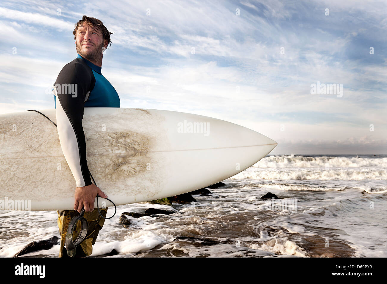 Surfer carrying board on beach Stock Photo - Alamy