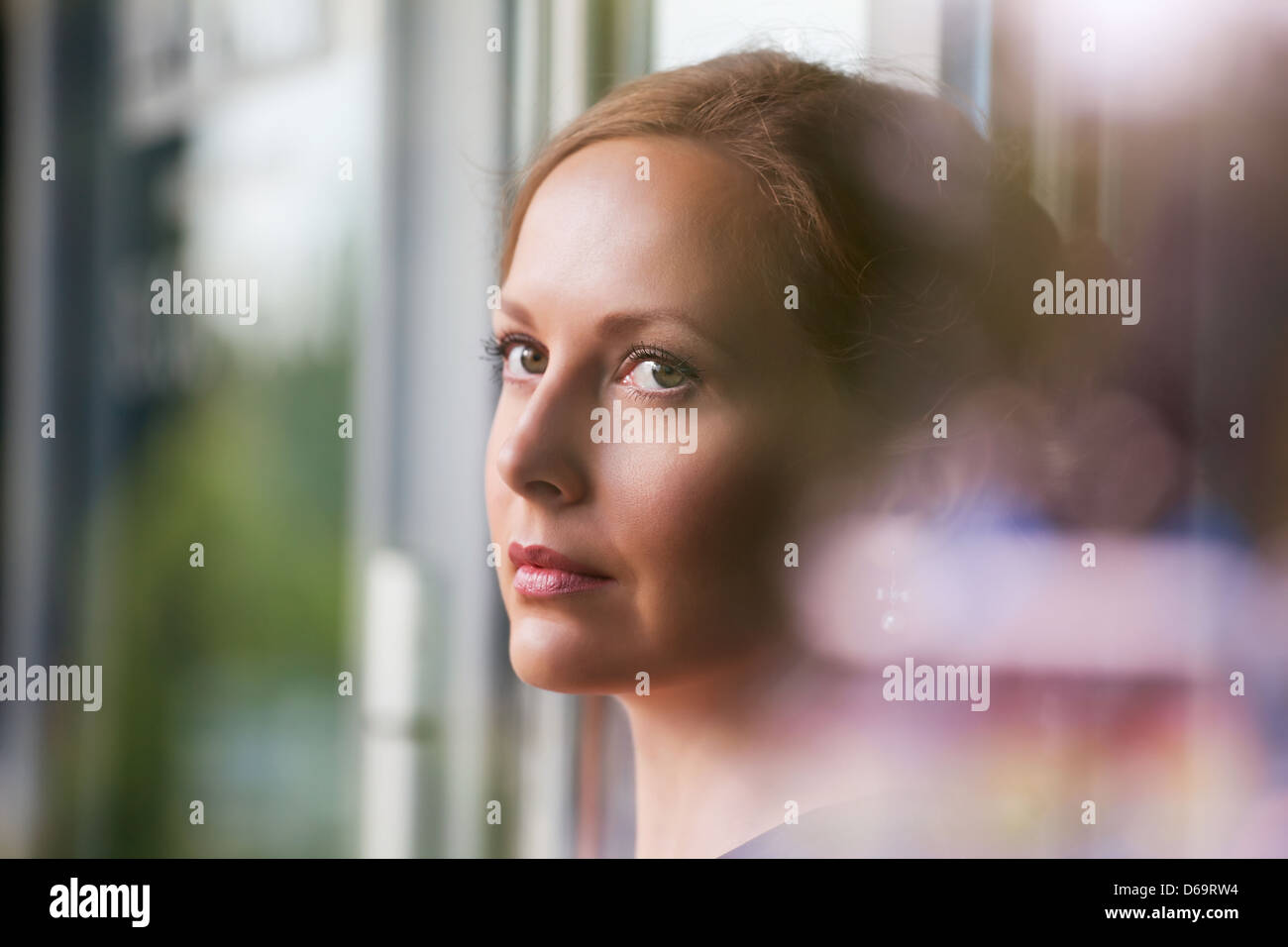 Woman looking through a window Stock Photo - Alamy
