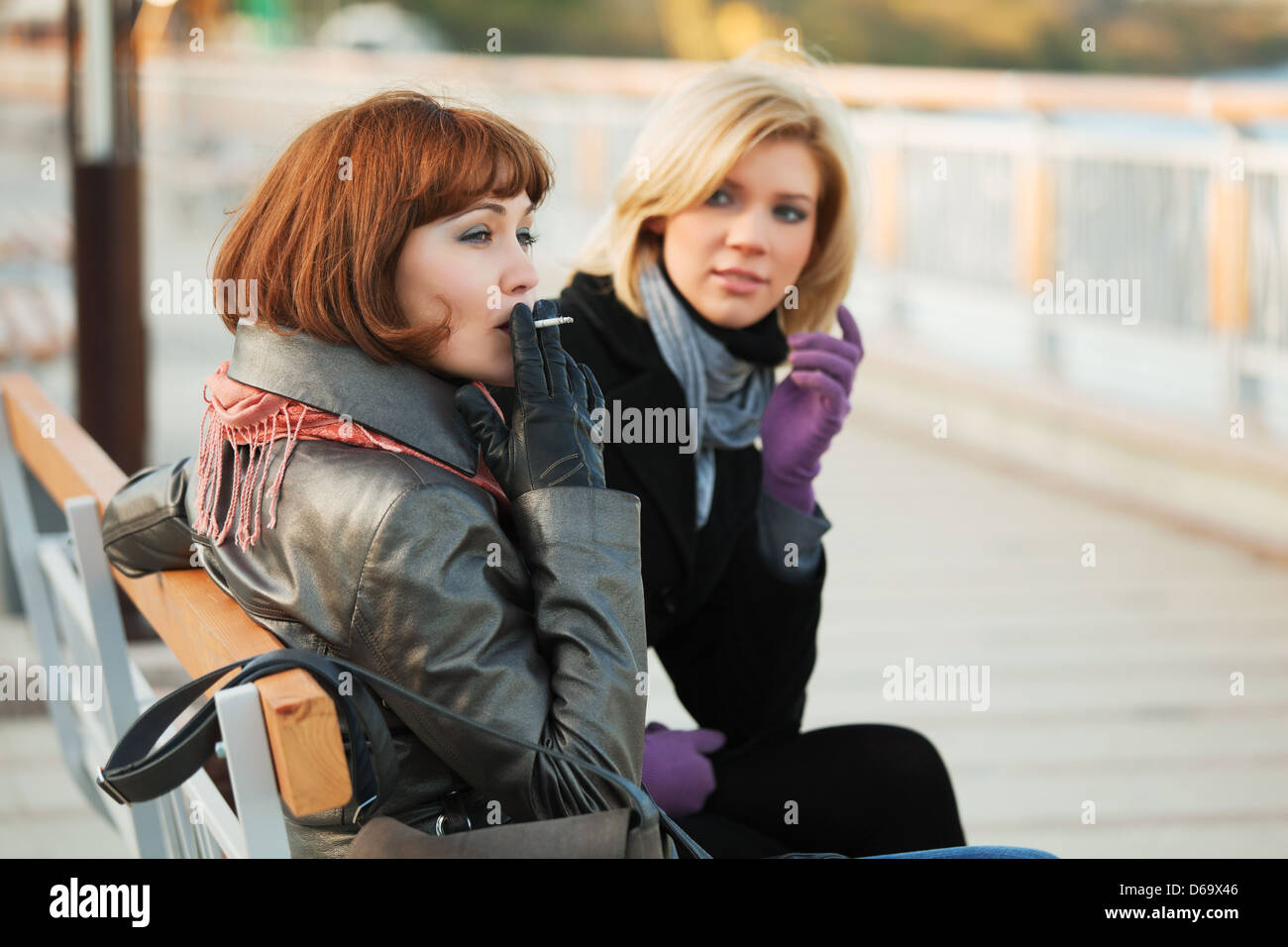 Two young women sitting on a bench Stock Photo - Alamy