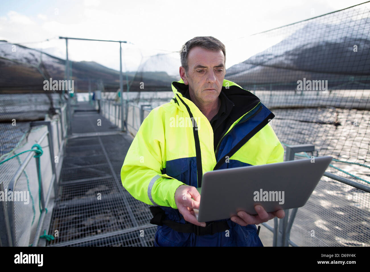 Worker at salmon farm in rural lake Stock Photo - Alamy