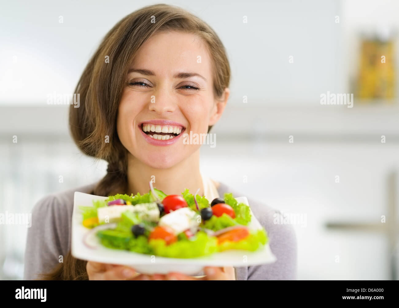 Smiling young woman showing fresh salad Stock Photo - Alamy