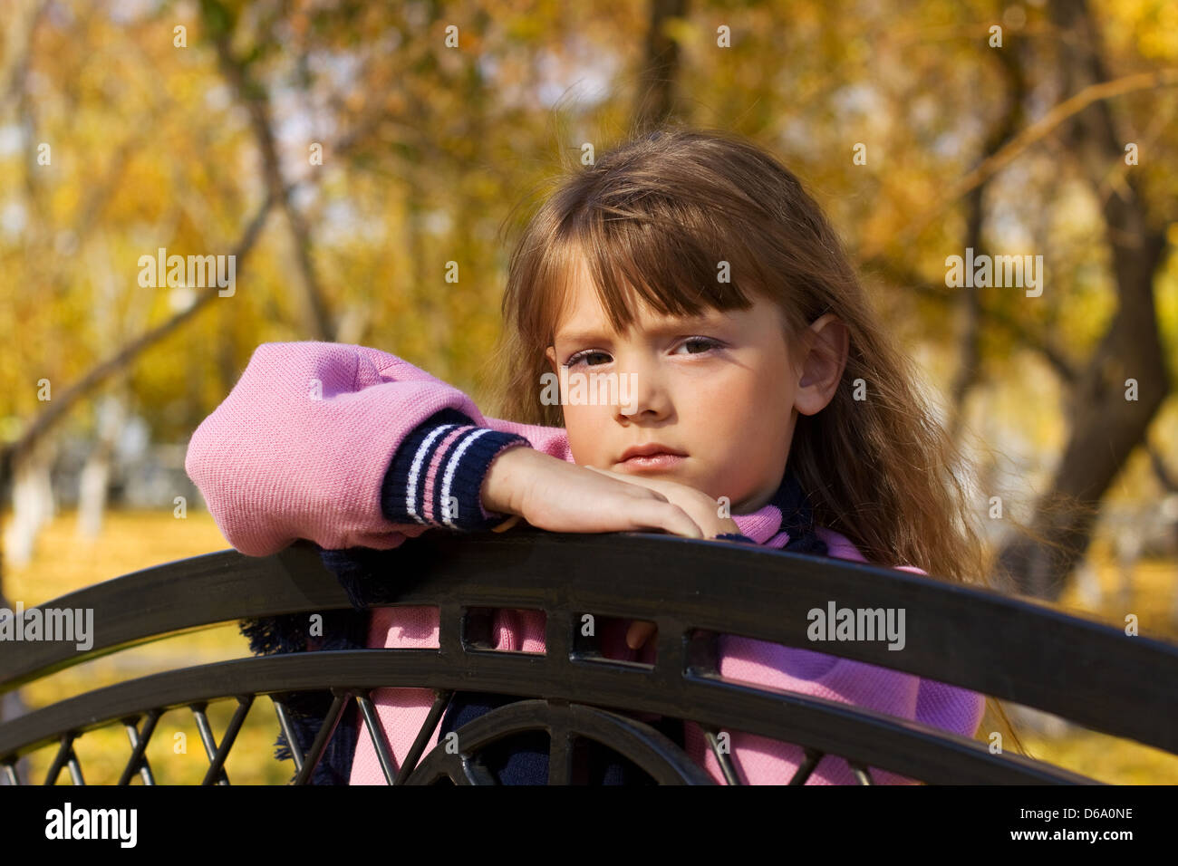 Little girl leaning on a bench Stock Photo - Alamy