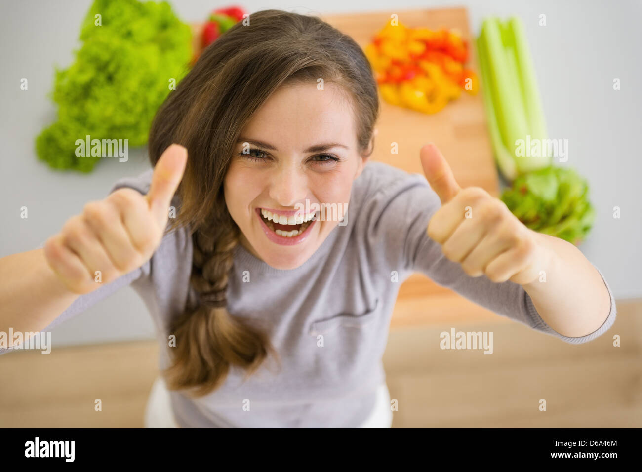 Happy young housewife in modern kitchen showing thumbs up Stock Photo ...