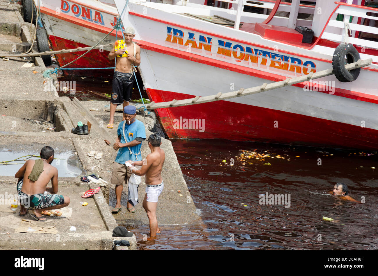 Brazil, Amazon, Manaus. Busy waterfront pier. Local workers bathing in ...
