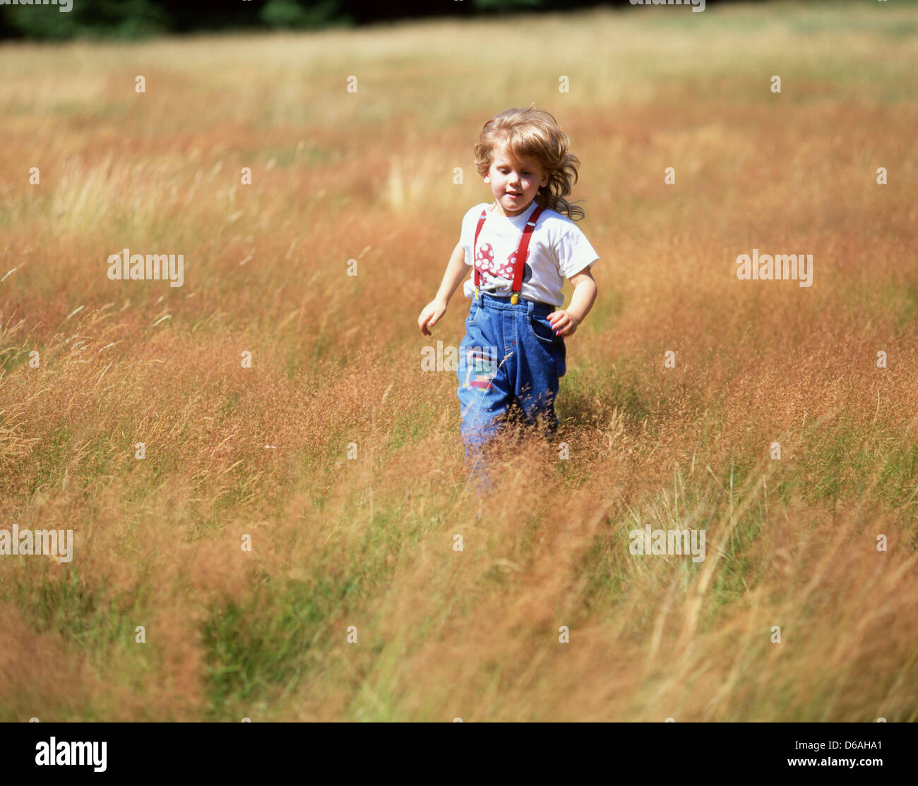 Young girl running through grassy field, Winkfield, Berkshire, England ...