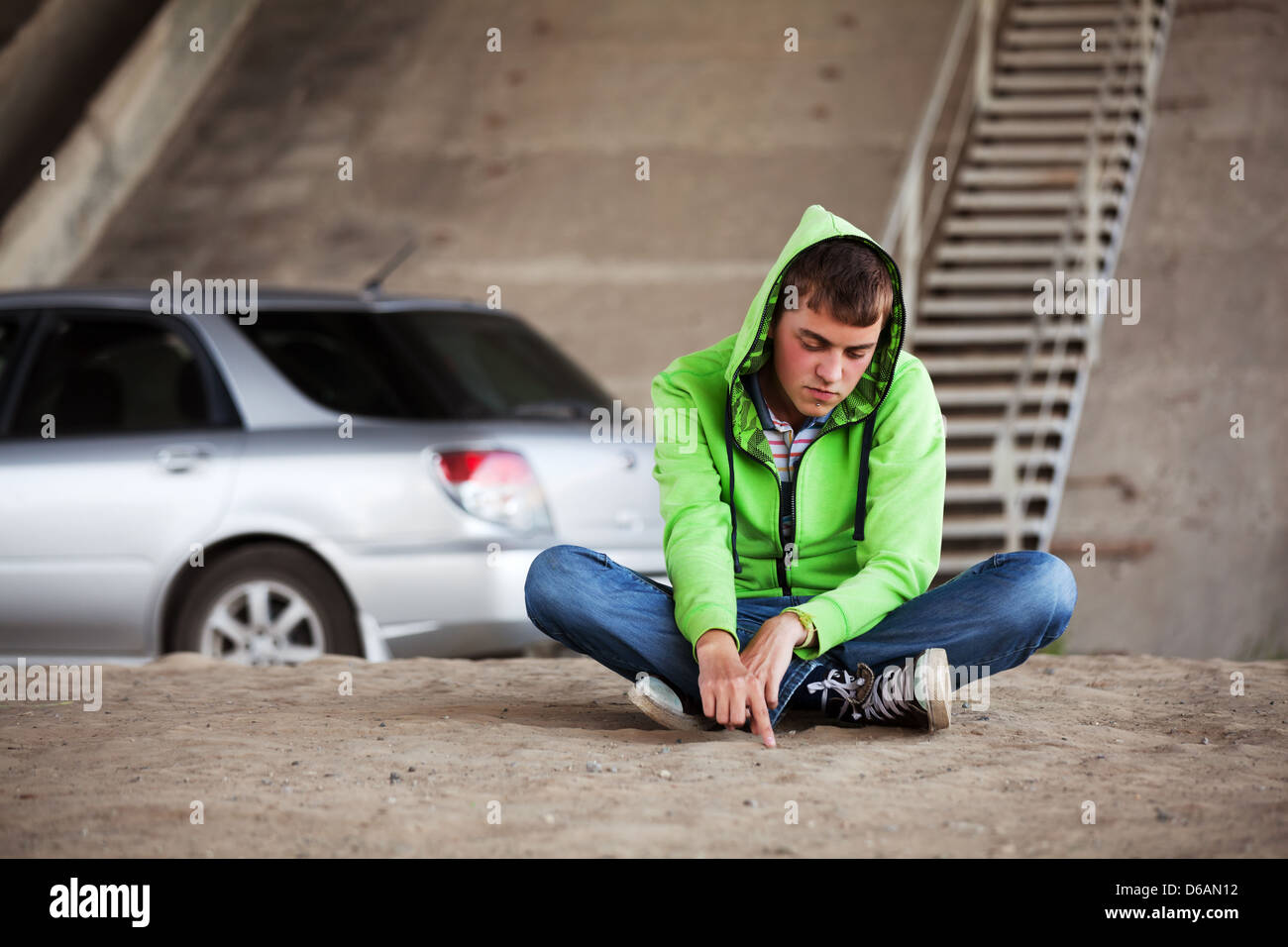 Young man sitting against a car Stock Photo - Alamy