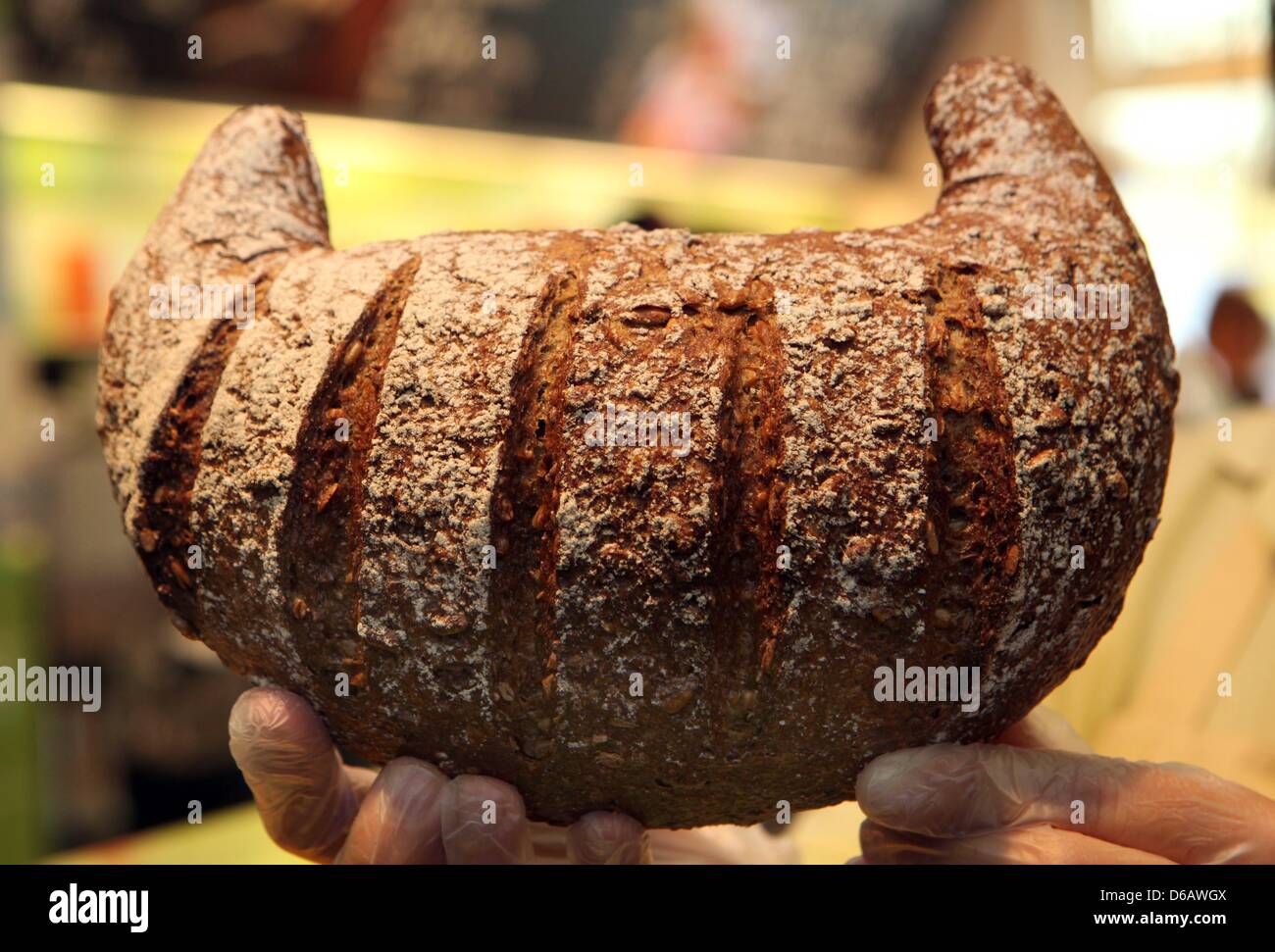 A saleswoman presents a fresh organic canoe bread at a Fahland Bakery ...
