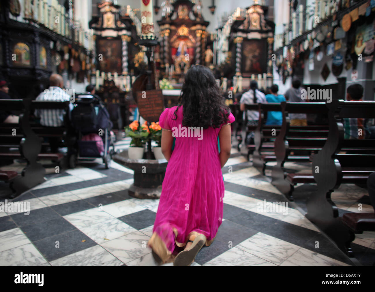 A woman kneels in front of an altar at the Christian pilgrimage site ...