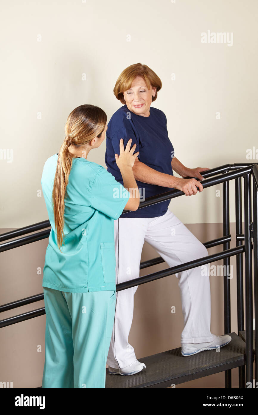 Physiotherapist doing kinesiotherapy with senior woman on railing Stock ...