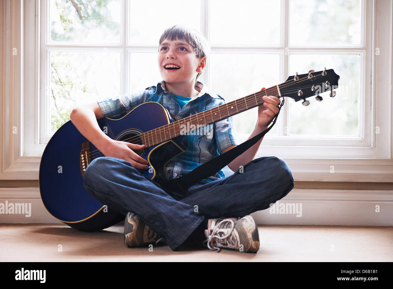 Boy playing guitar on floor Stock Photo - Alamy