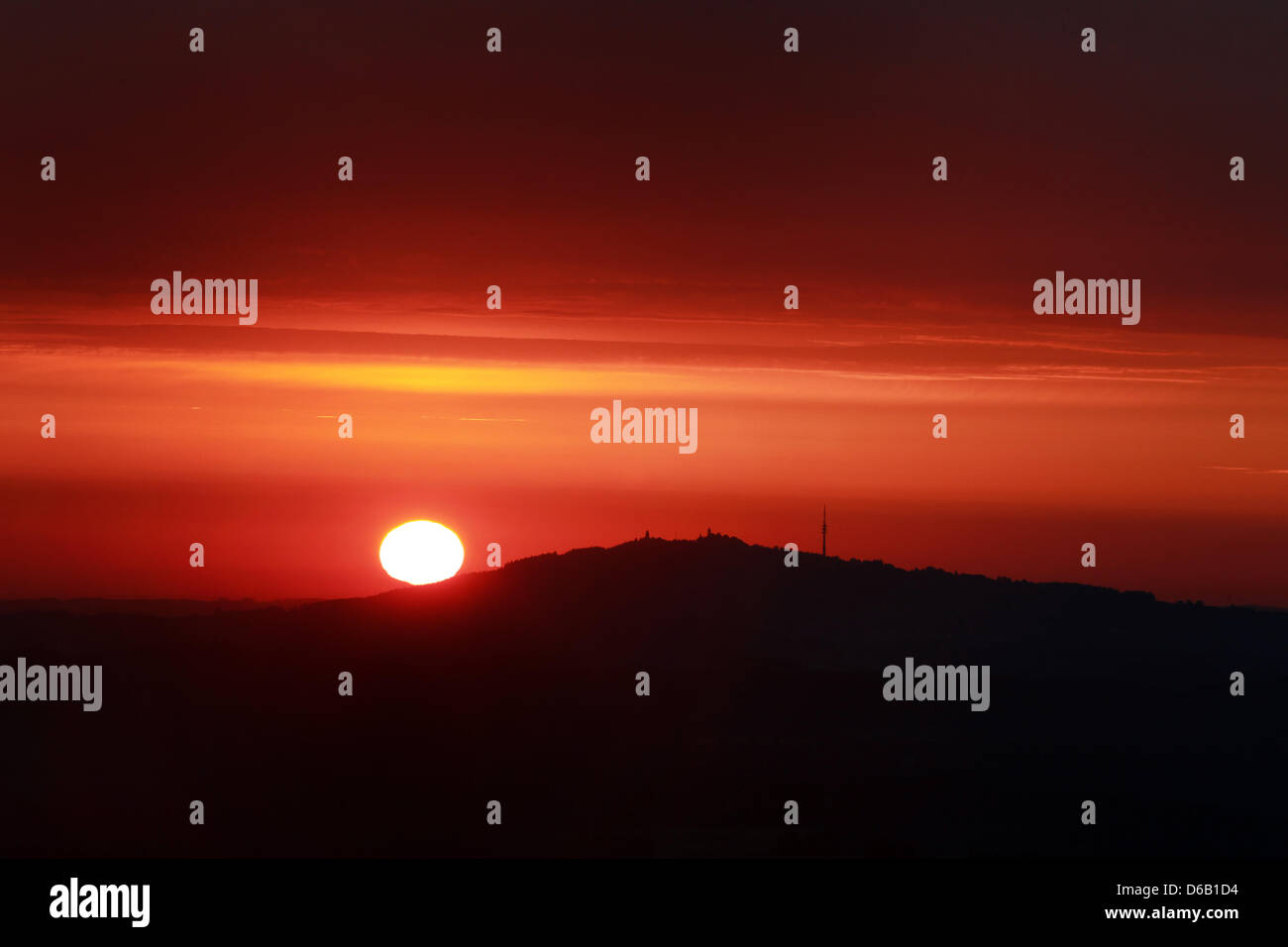 The rising sun illuminates the sky above the Hoher Peissenberg mountain ...
