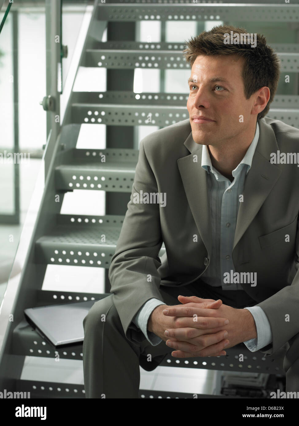 Businessman sitting on steps in office Stock Photo - Alamy