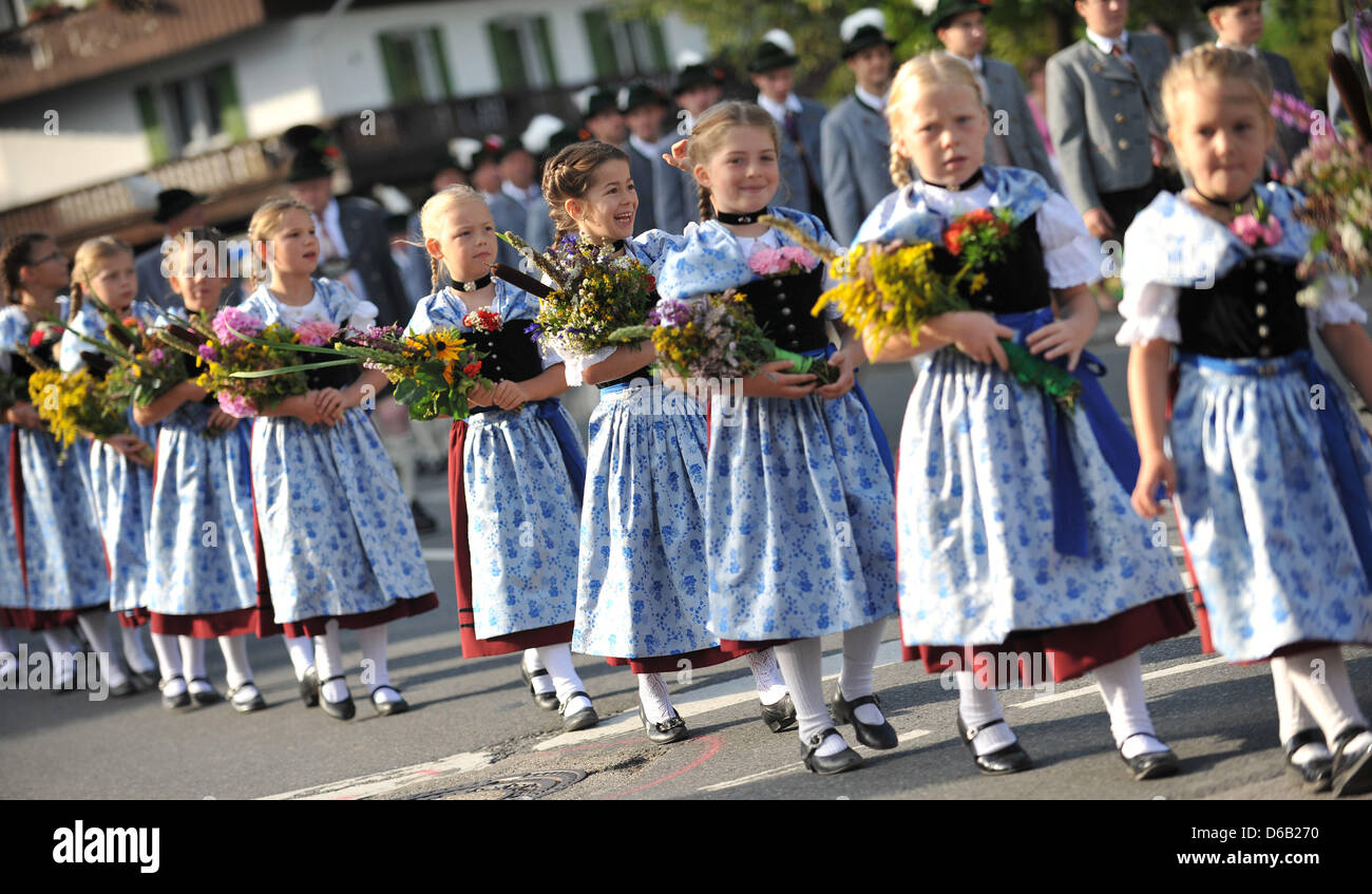 Girls wear traditional Bavarian costumes and carry bouquets of herbs ...