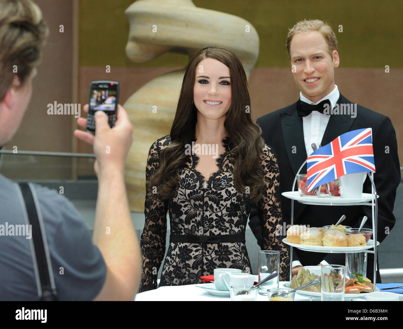 The wax figures of Prince William and Duchess Kate stand behind a table ...