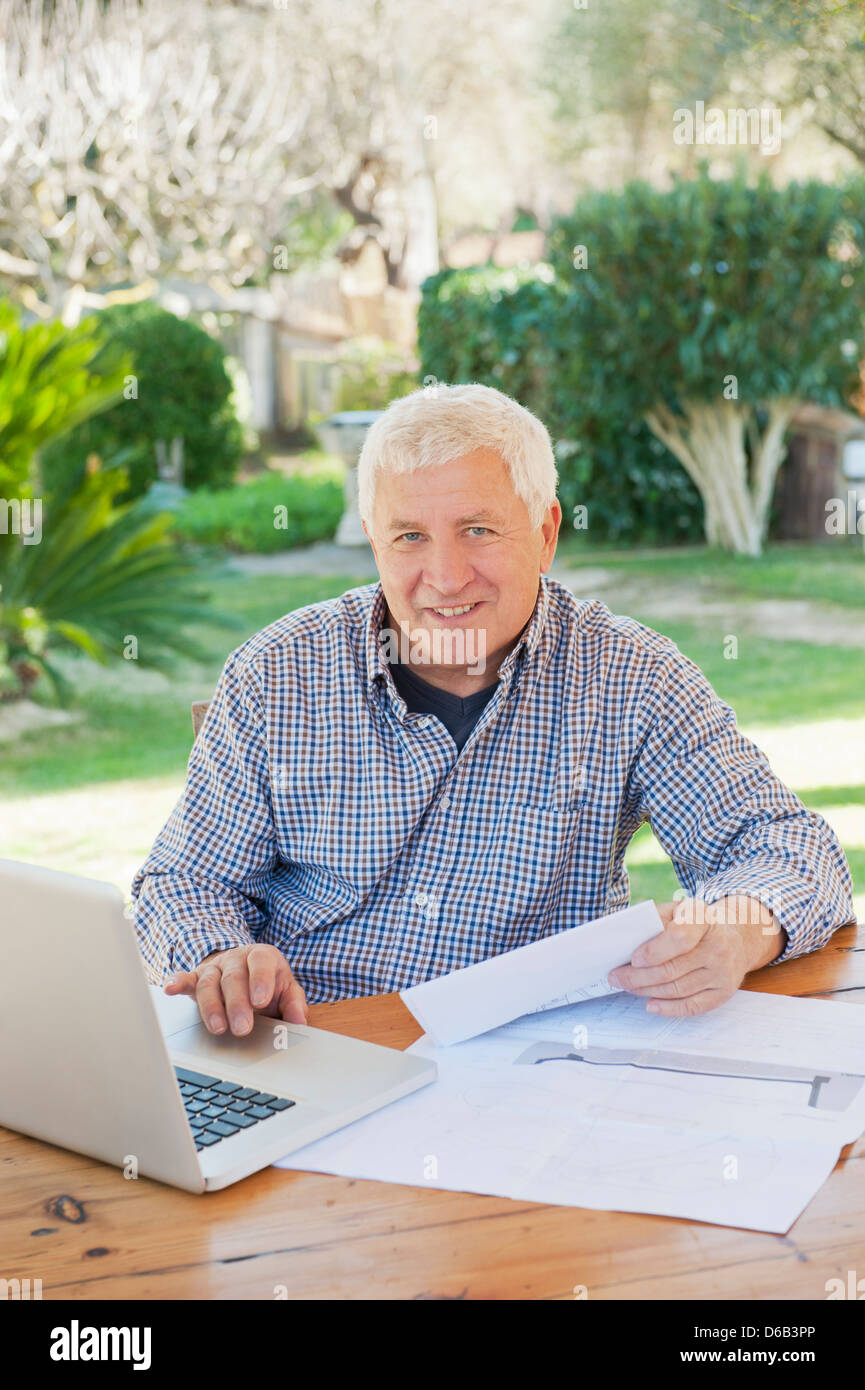 Older man paying bills on laptop Stock Photo - Alamy