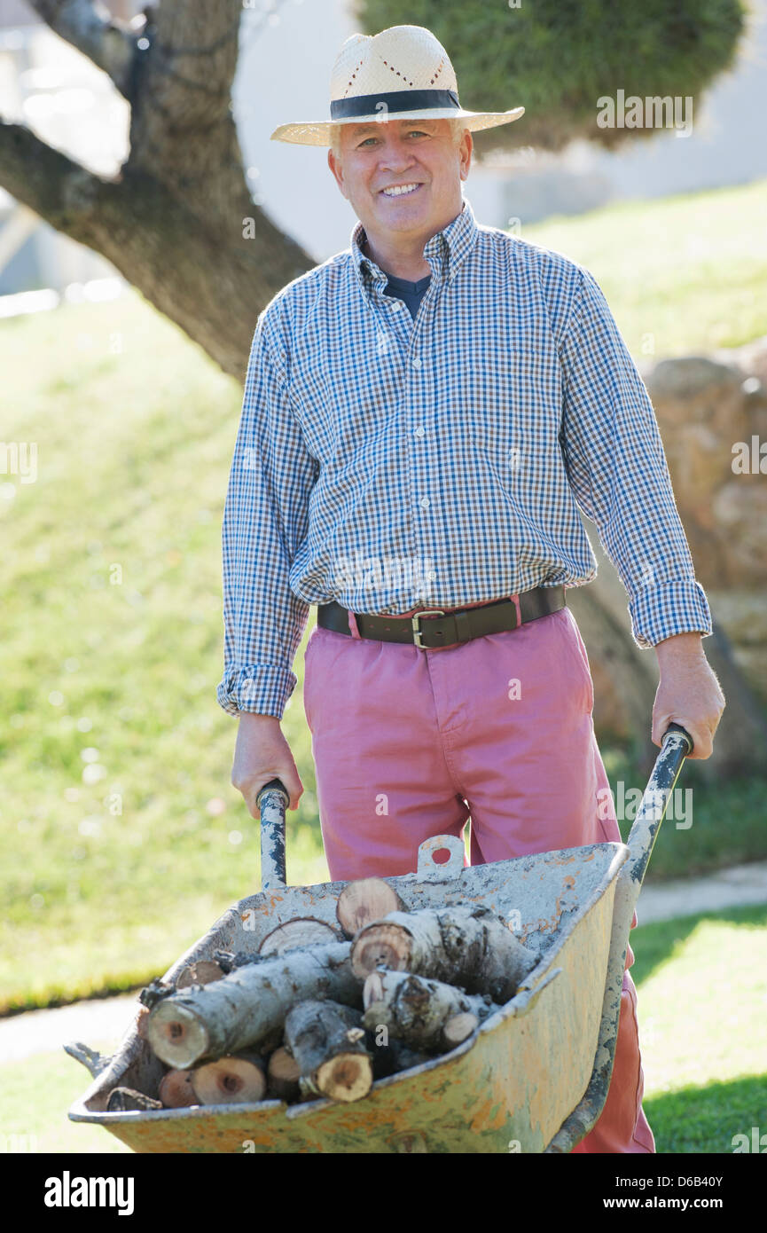 Older man pushing wheelbarrow outdoors Stock Photo - Alamy