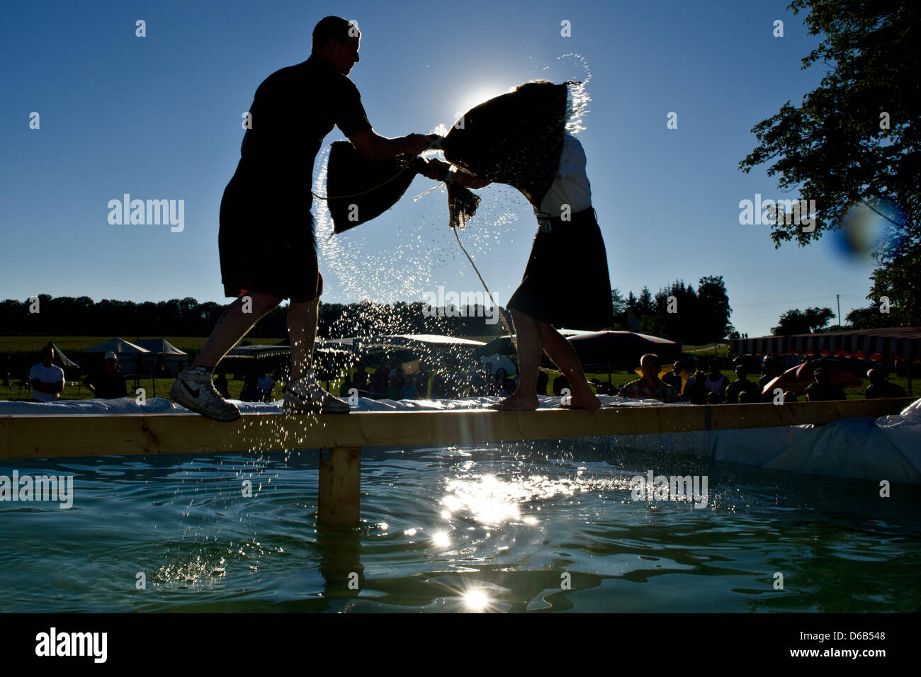 Two men try to push each other from a beam with jute bags during 'Upper ...